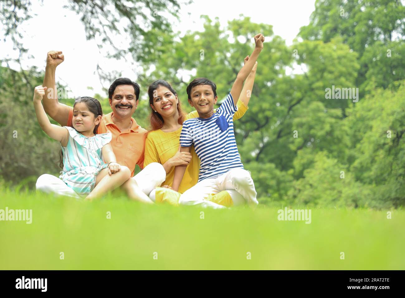 Happy Indian family with a girl and boy child sitting together on grass ...