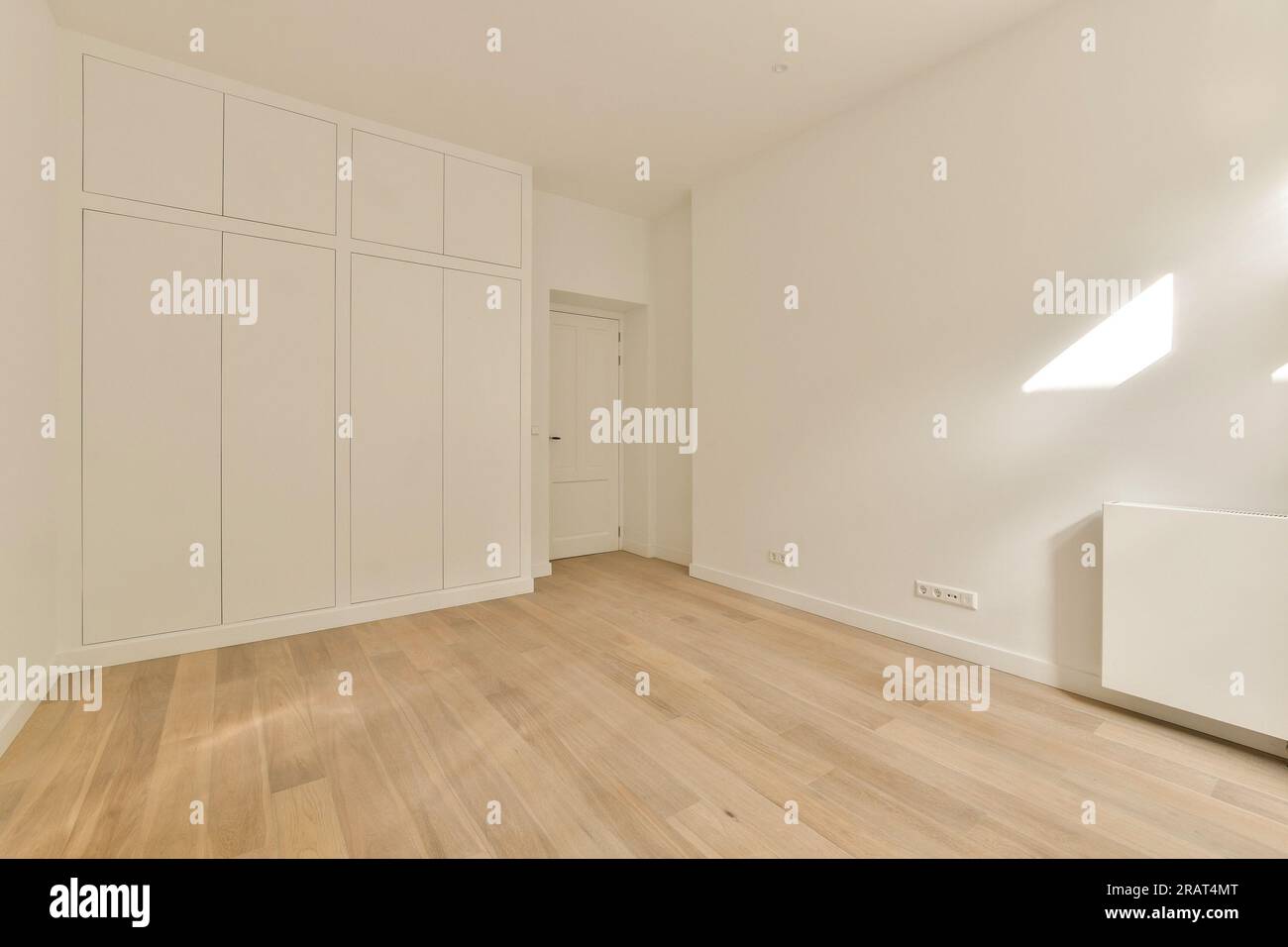 an empty room with wood floors and white cabinets on the wall to the ...