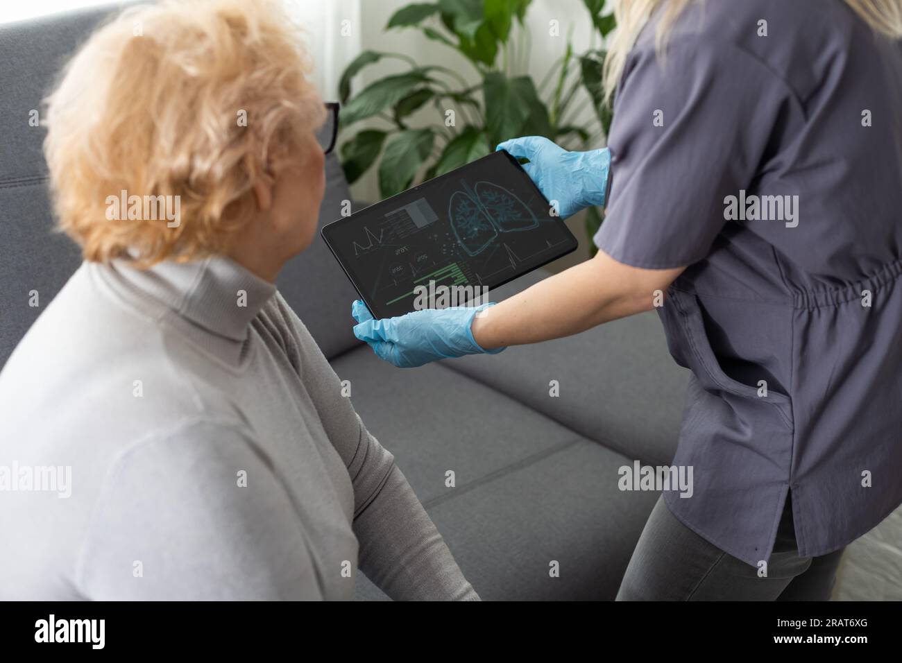 Serious GP doctor showing tablet screen to old 70s female patient ...