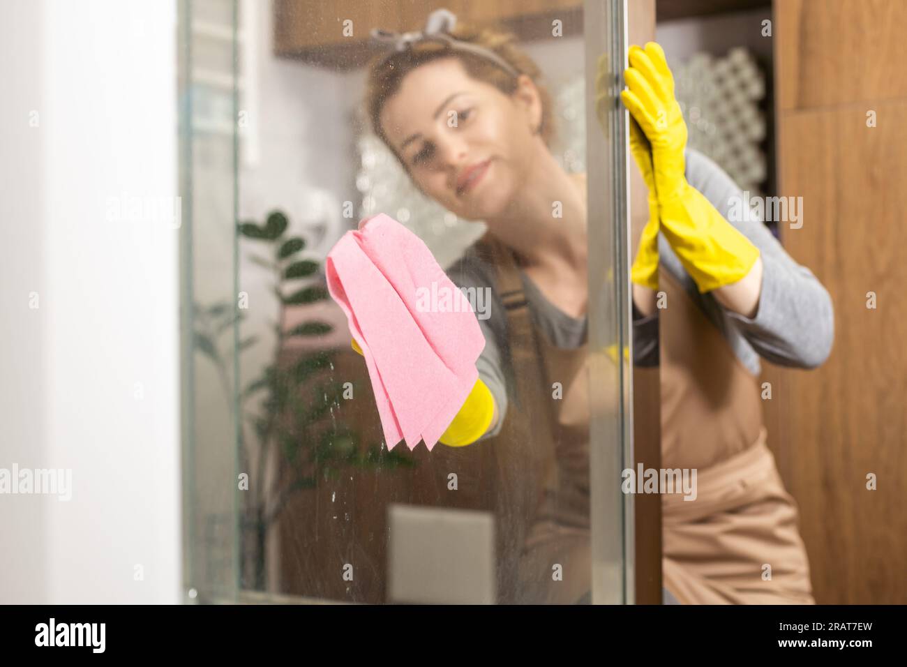 Woman cleaning and polishing the kitchen worktop with a spray detergent ...