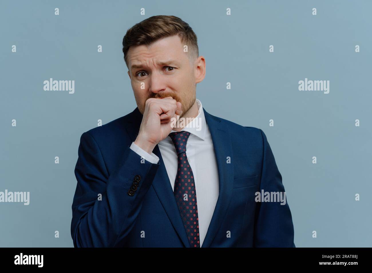 Stressed businessman in suit, biting fist emotionally, against light ...