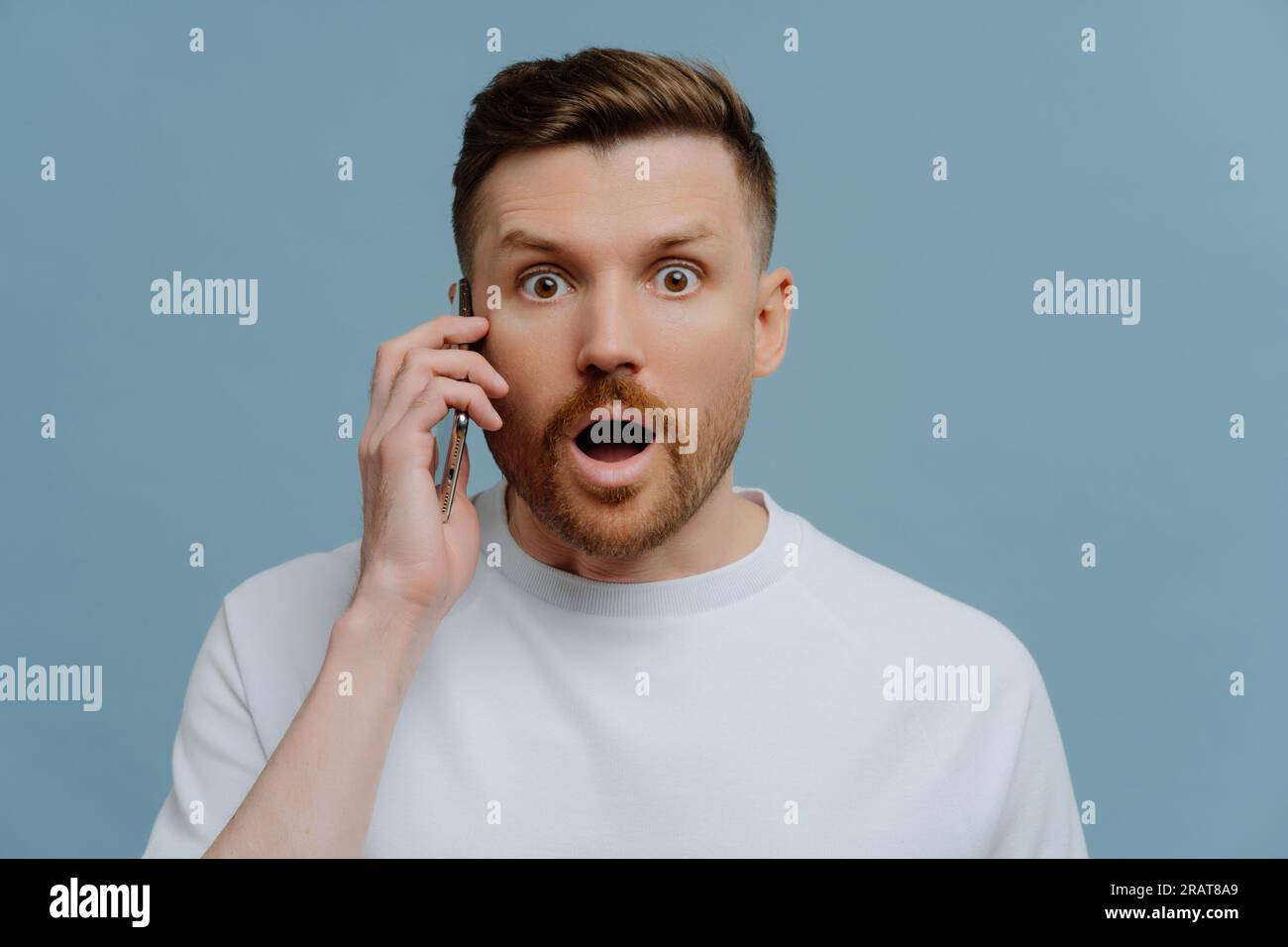 Stupefied man, phone to ear, reacts to shocking news. Technology and ...