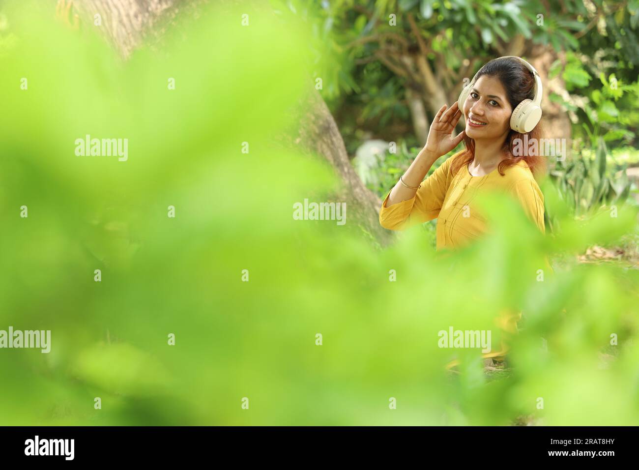 Slim beautiful woman listening and enjoying to music in a park using ...