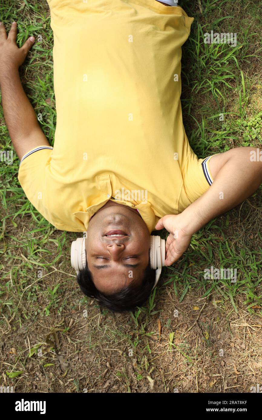 A young mid aged obese man listening and enjoying to music in a park ...