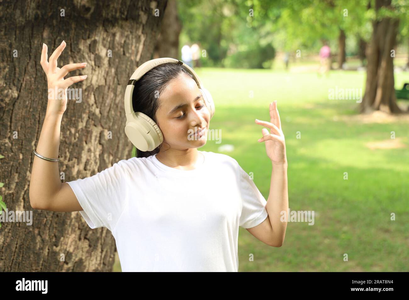 Young teenage girl listening and enjoying to music in a park using her ...