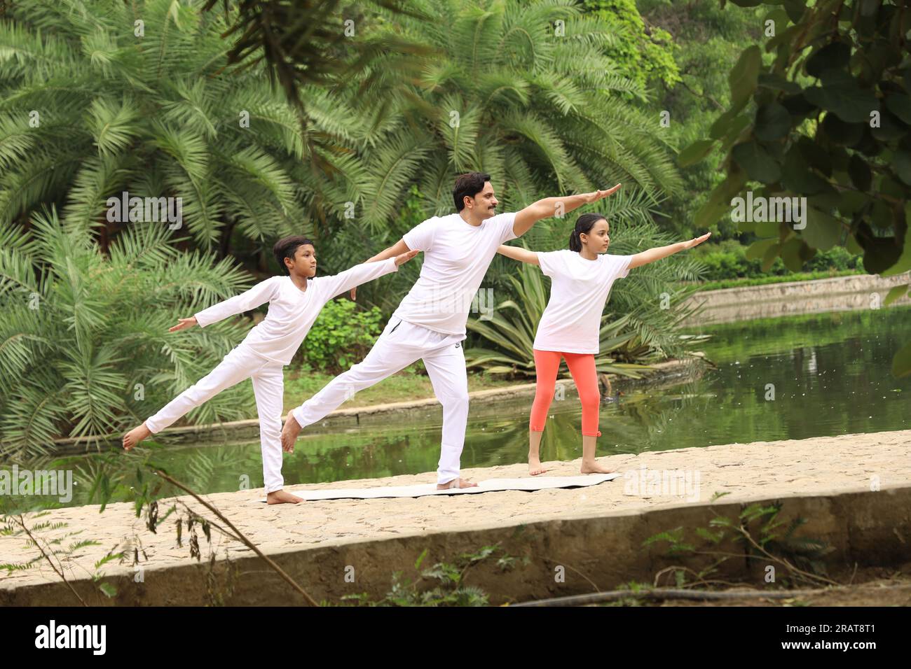 Young fit man exercising and doing Yoga poses in green environment ...