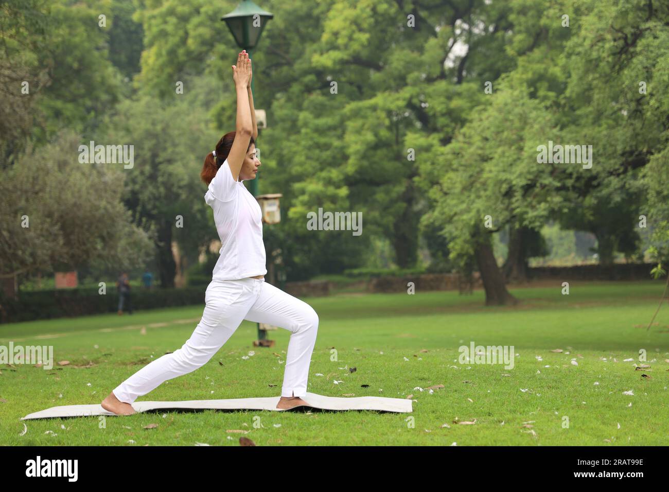 Young woman exercising and doing Yoga poses in green serene environment ...