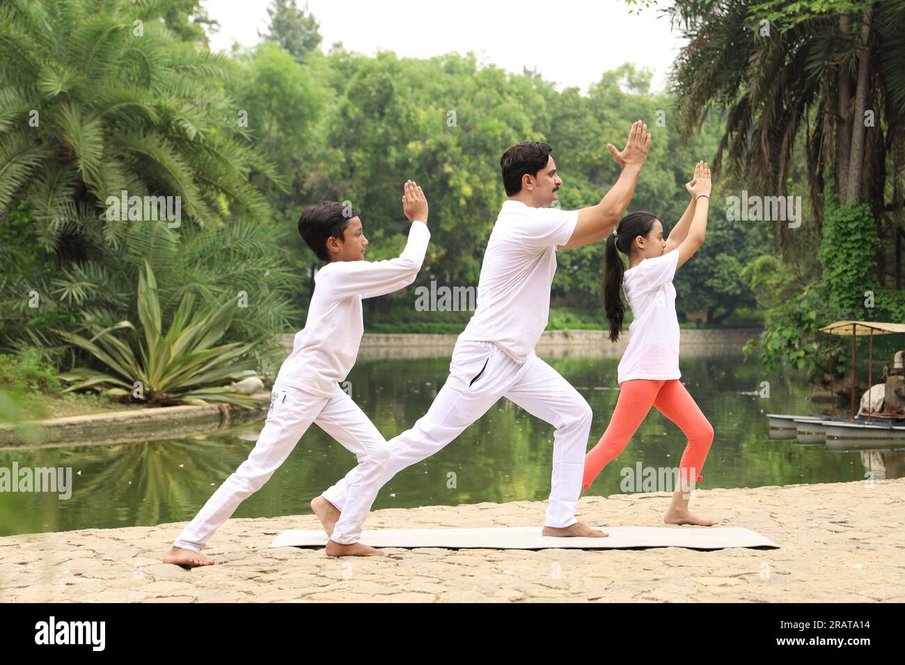 Trainer exercising and teaching kids the yoga poses in green ...