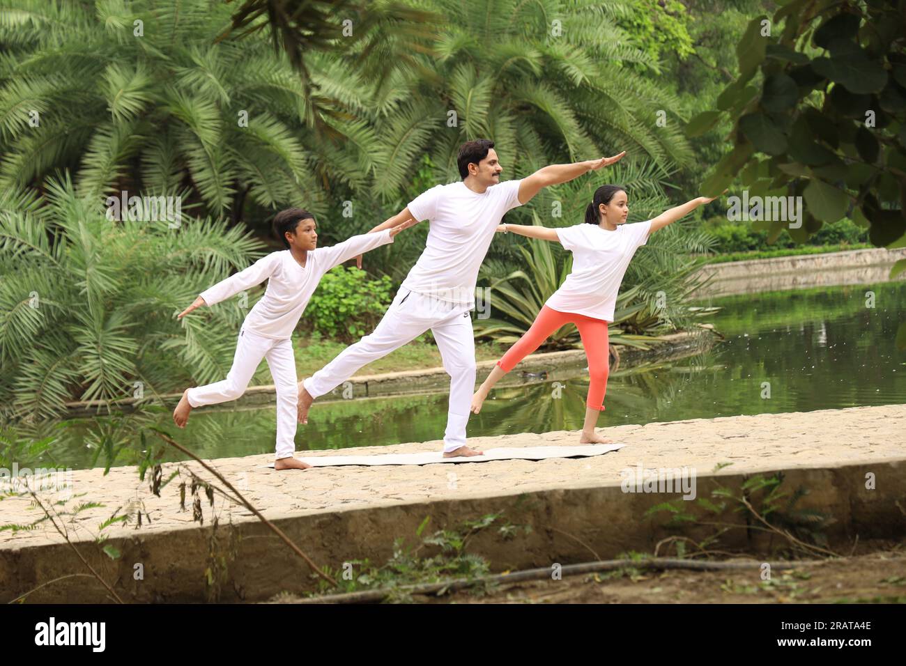 Trainer exercising and teaching kids the yoga poses in green ...