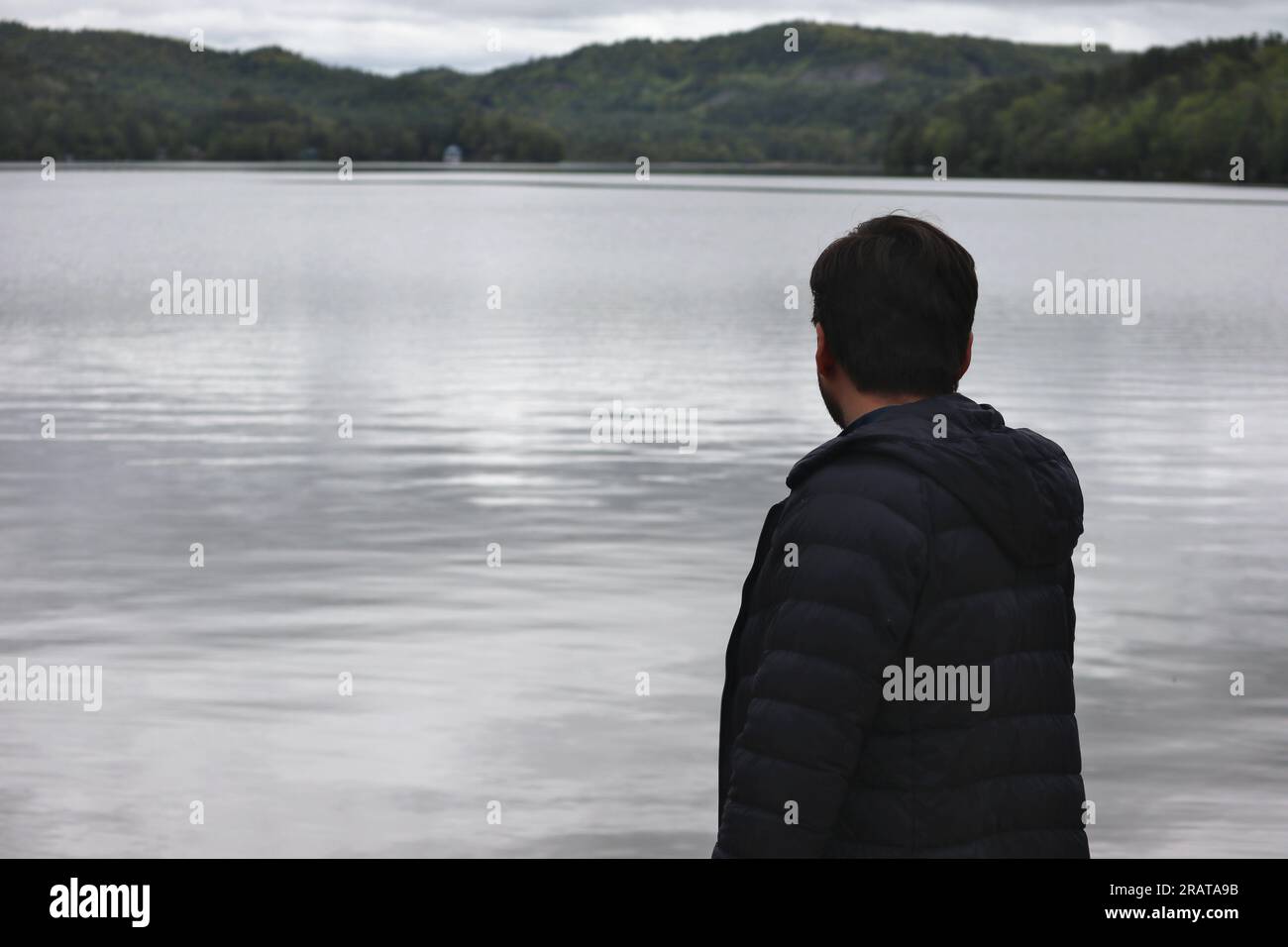 man looking at lake in the evening (travel photo with mountains, hills ...
