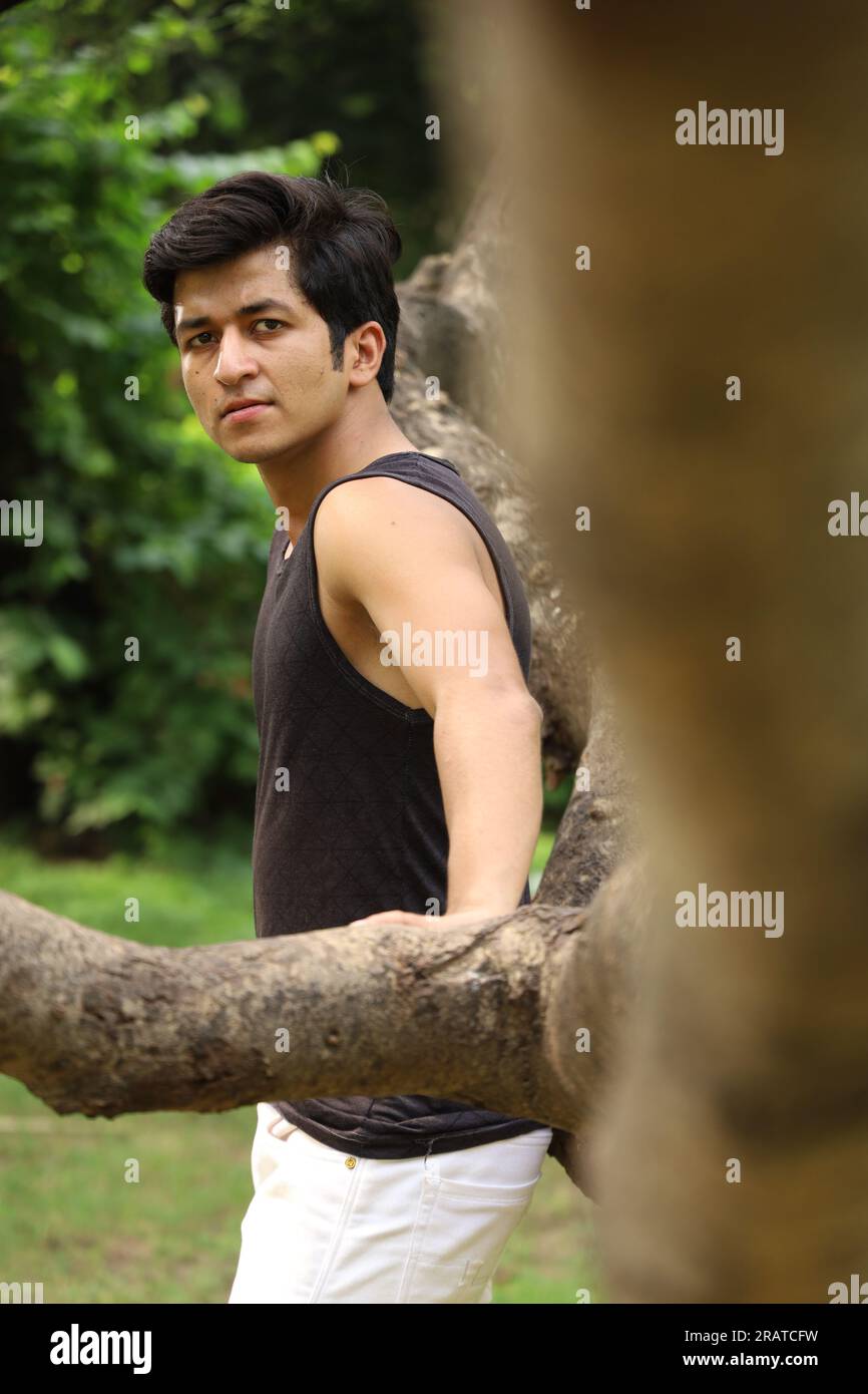 Young teen boy posing in the park in greens and serene atmosphere ...
