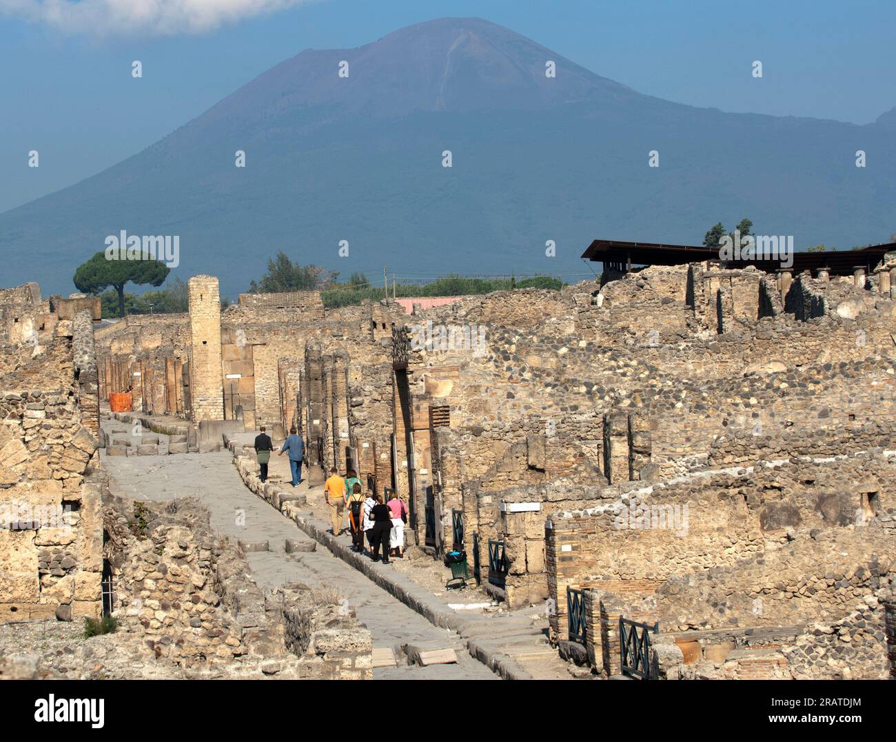 Tourists walk the streets of historic Pompeii with Mount Vesuvius in ...