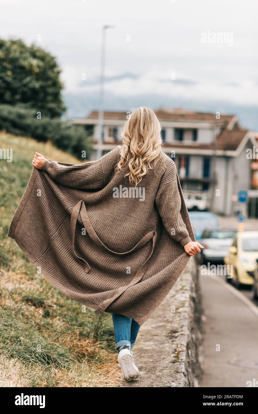 Outdoor portrait of fashion woman wearing long beige cardigan, back ...