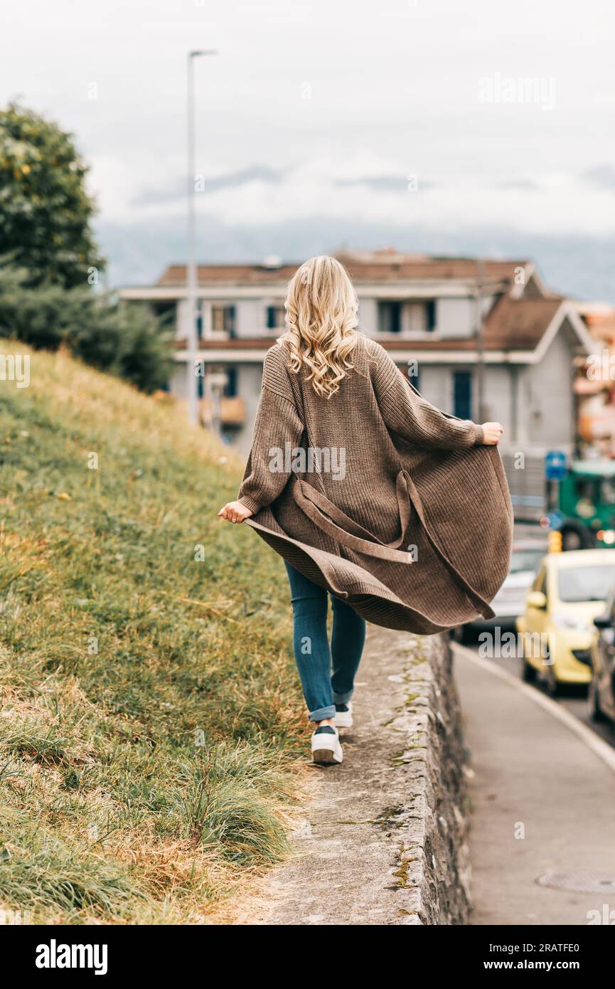 Outdoor portrait of fashion woman wearing long beige cardigan, back ...