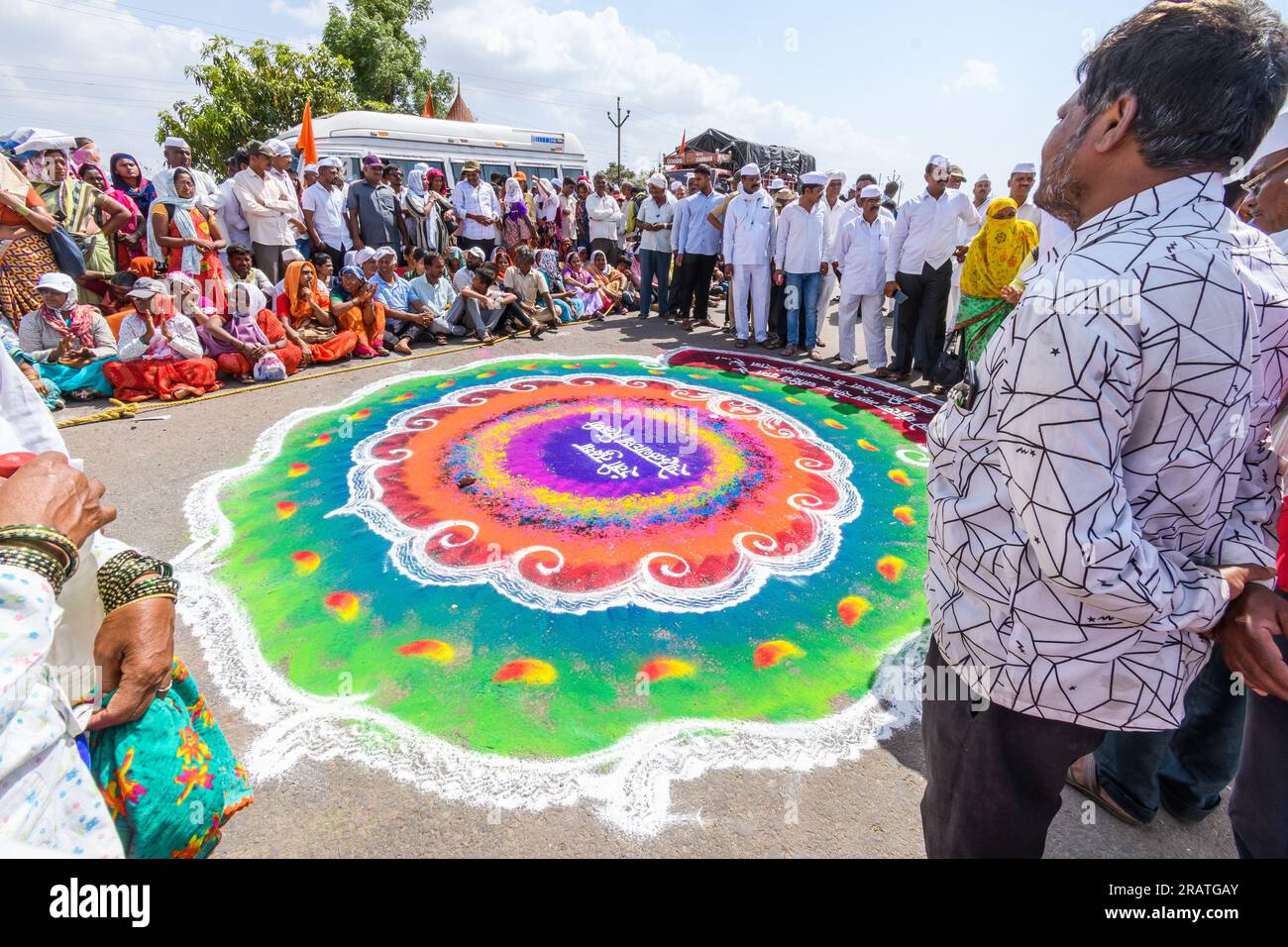 A group of people surrounding the rangoli drawn on the road during ...