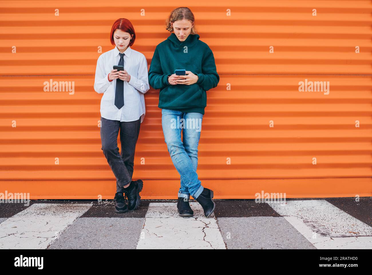 Two caucasian teen friends boy and a girl browsing their smartphone ...