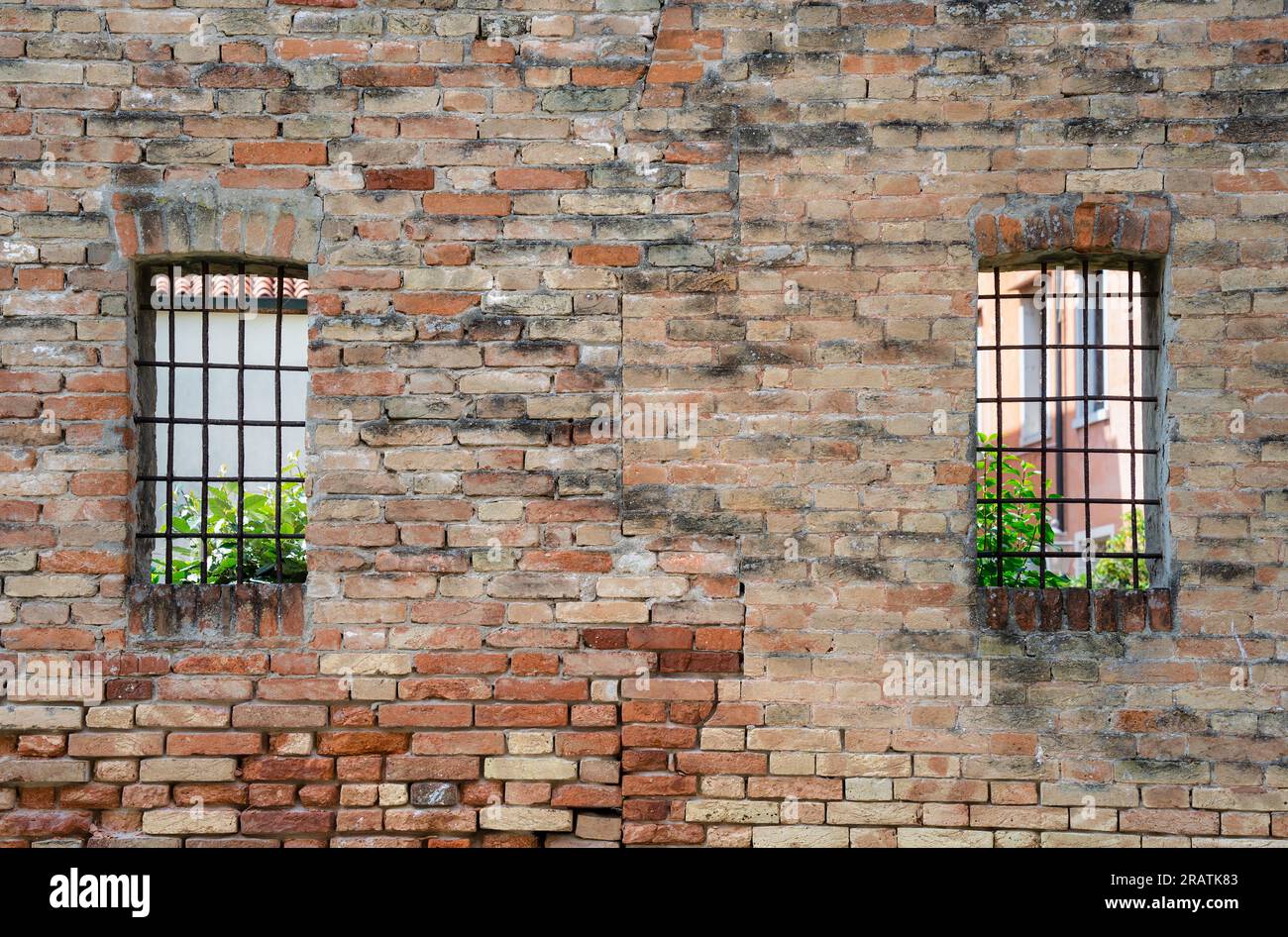 Old red brick wall with two rusted iron grill windows Stock Photo - Alamy