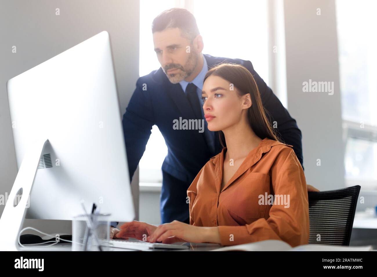 Focused employees young woman and middle aged man looking at computer ...