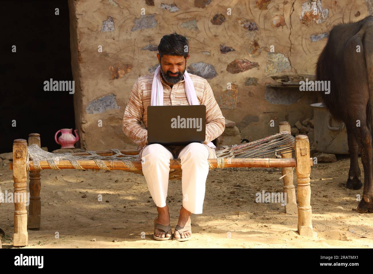 Happy rural Indian villager sitting with laptop in kurta pajama in a ...