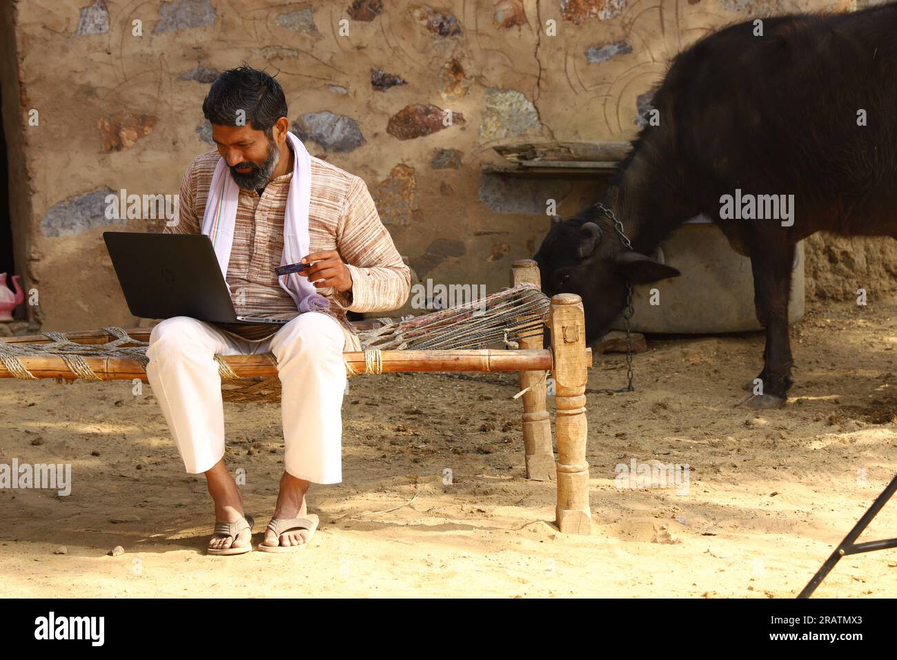 Happy rural Indian villager sitting with laptop in kurta pajama in a ...