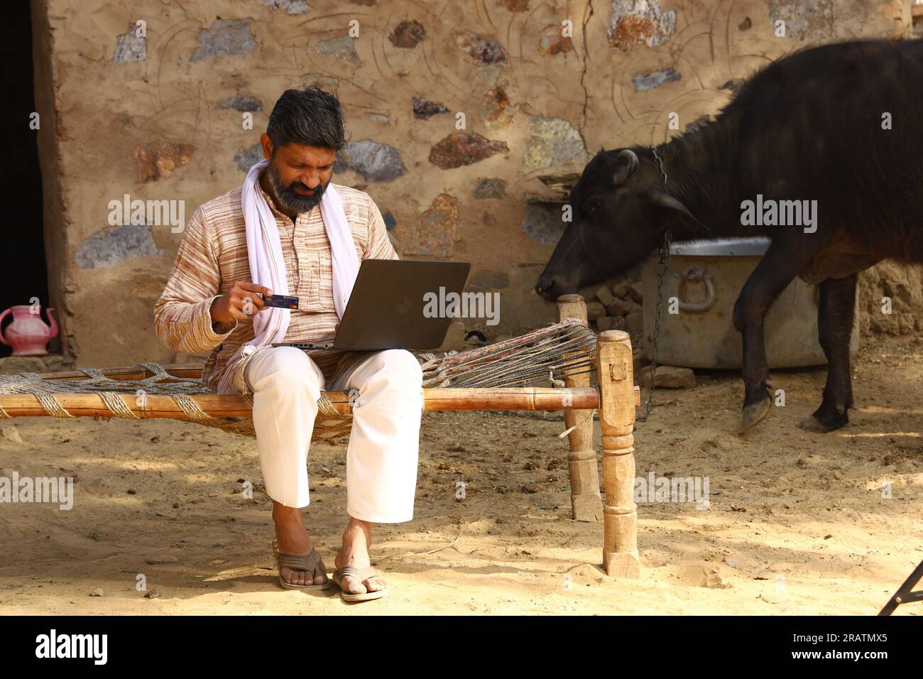 Happy rural Indian villager sitting with laptop in kurta pajama in a ...