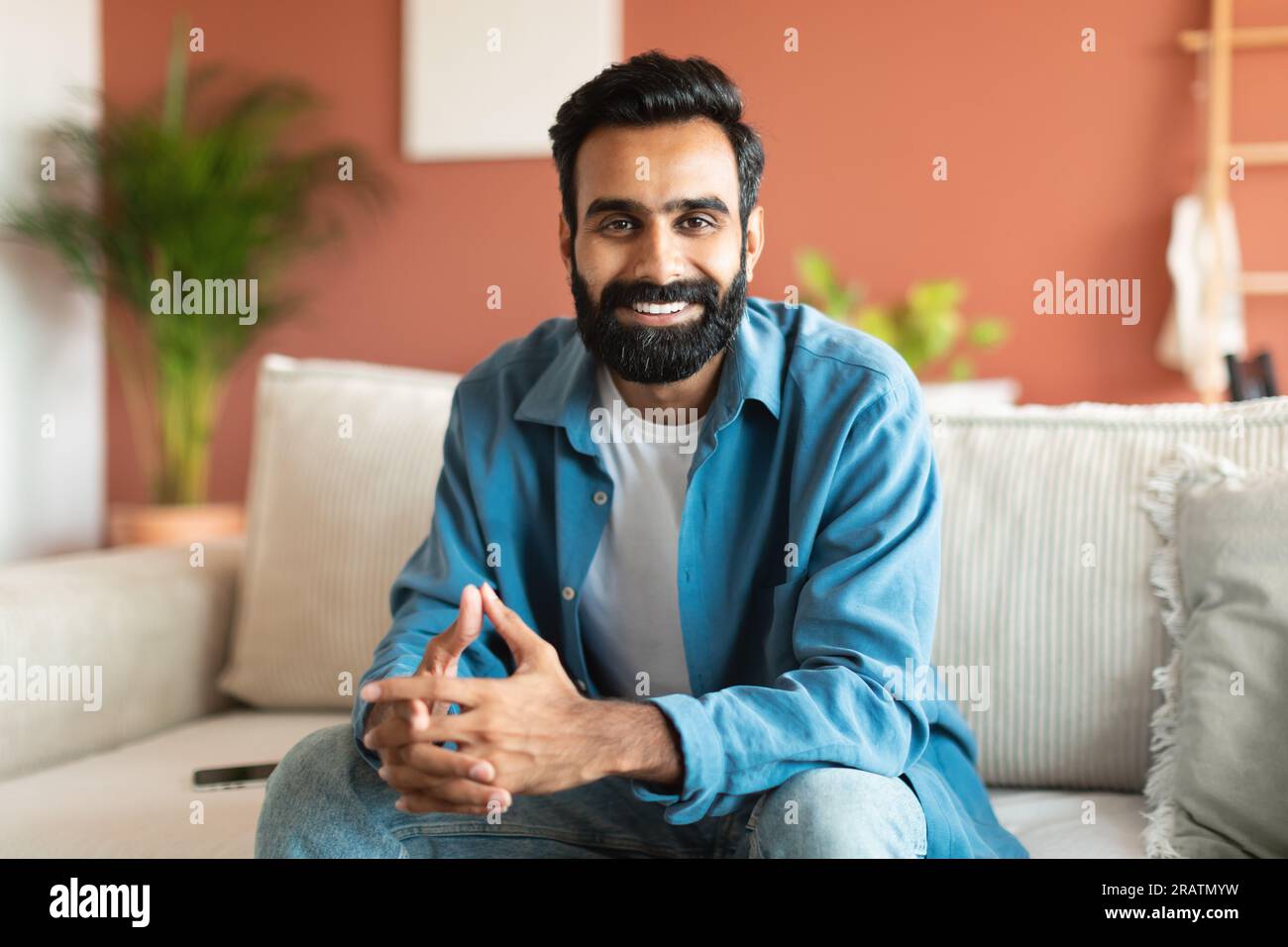 Lifestyle portrait of happy young indian man posing at home Stock Photo ...