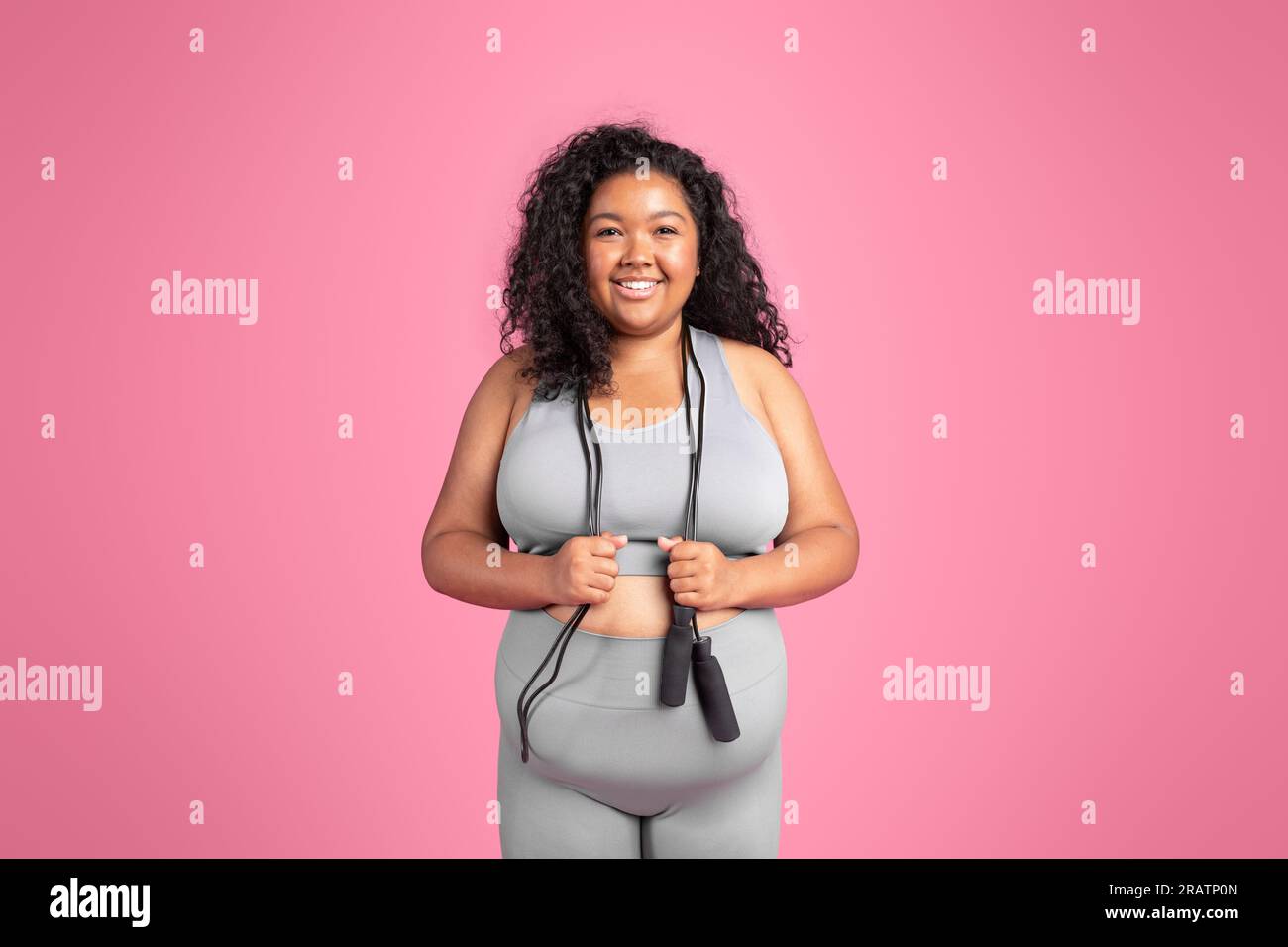 Excited black overweight woman in sportswear holding jump rope and ...