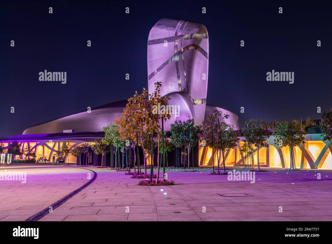 Illuminated modern building and square with trees in the center of Al ...