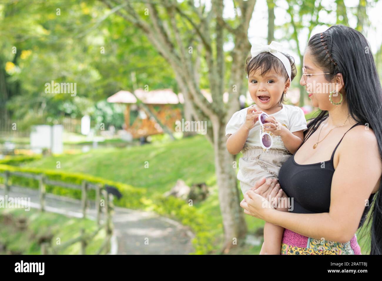 latina mother holding her smiling baby daughter and proudly admiring ...