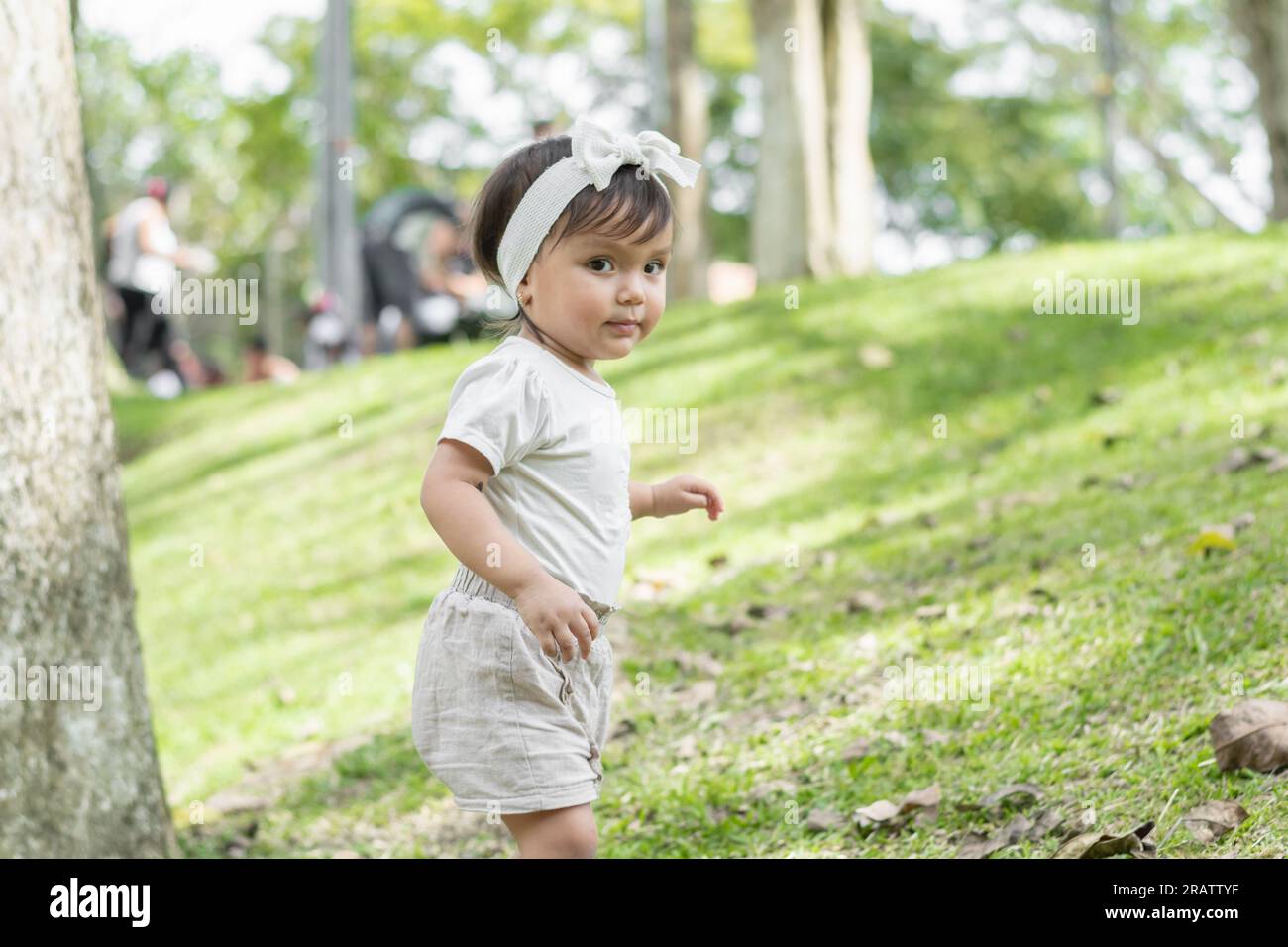 little brunette latina girl, walking in the park surrounded by green ...