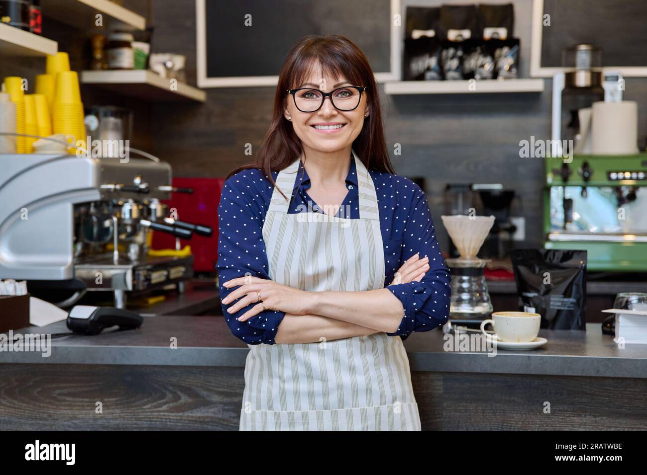 Portrait of female small business owner wearing apron near coffee shop ...