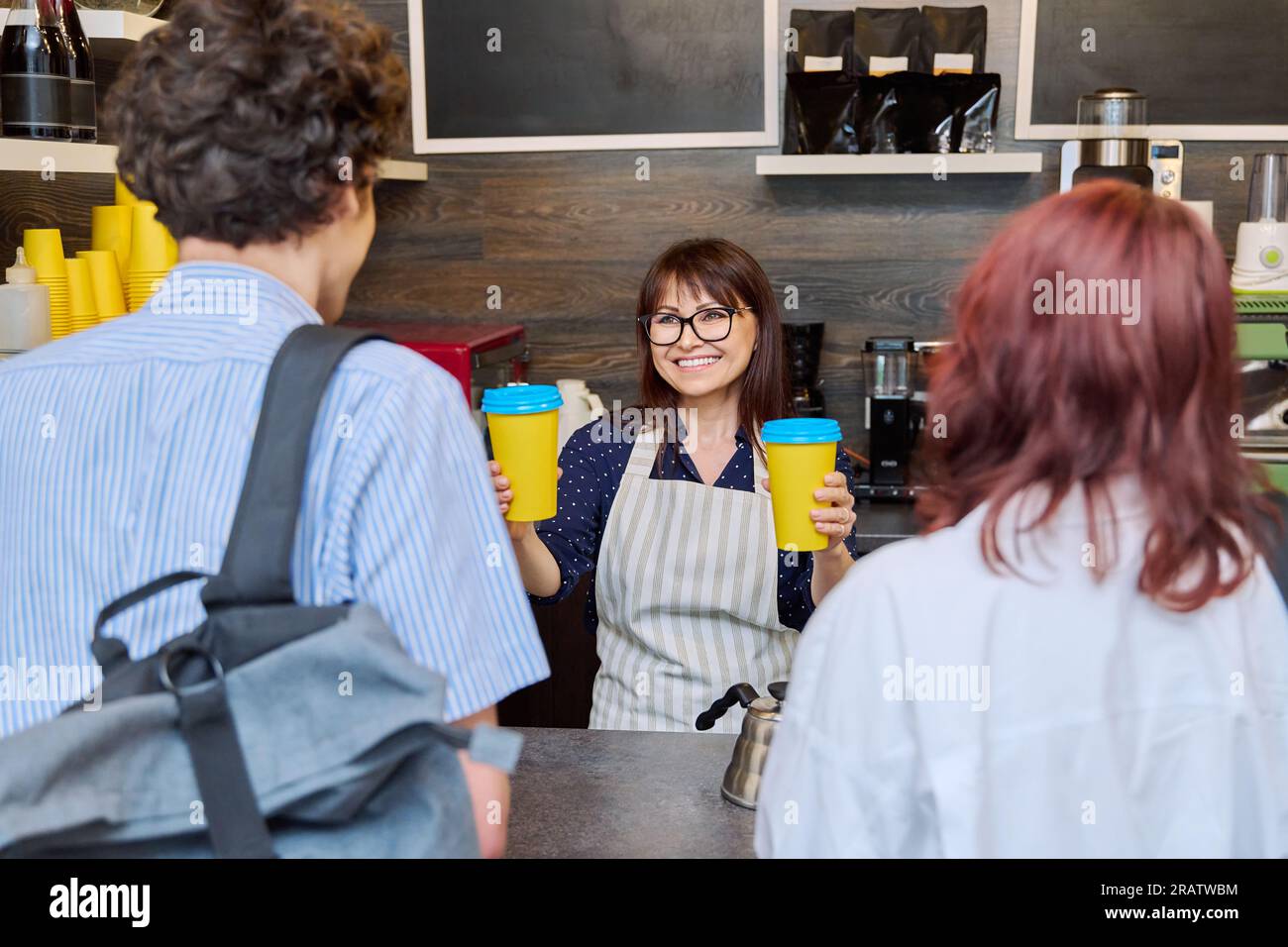 Female coffee shop worker serving customers giving paper cups of ...