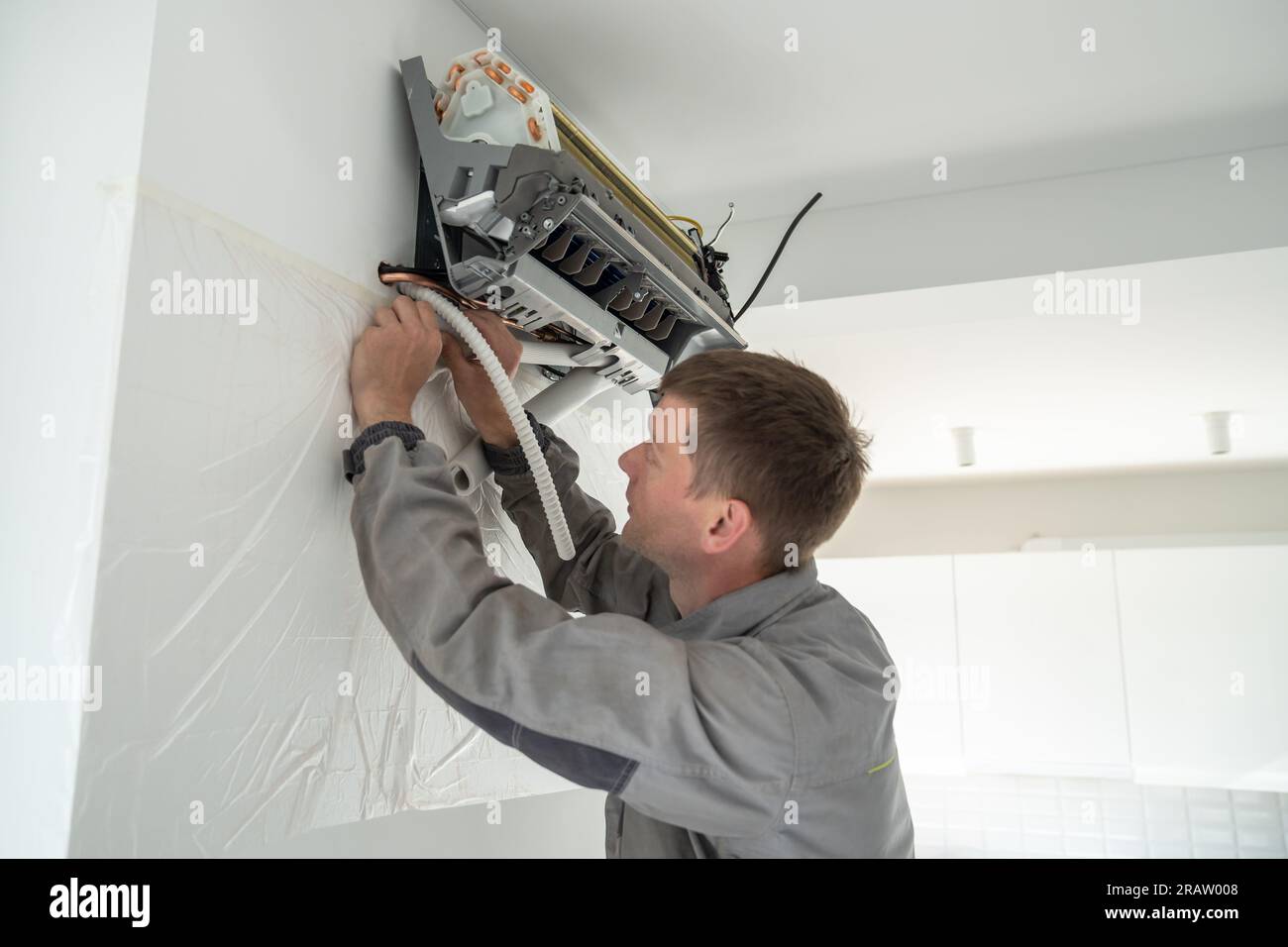 Installing air conditioner in house. Man specialist wearing work ...