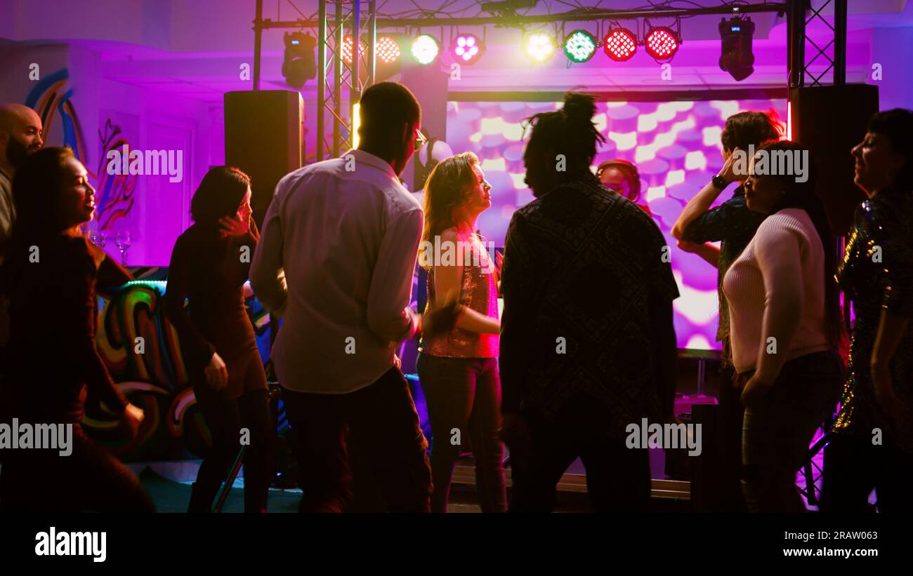 Cool dancers showing dance moves on funky beats, having fun with people at social gathering in ...