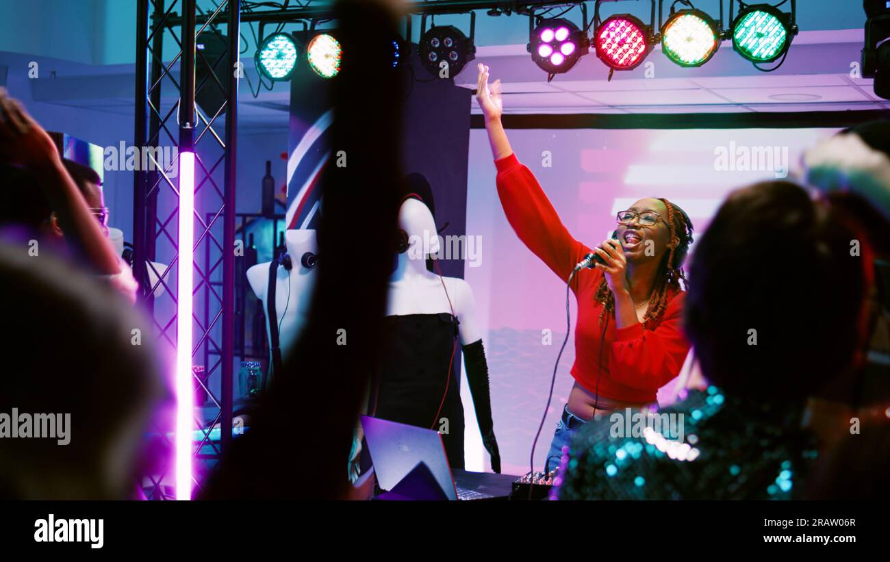 Young woman working as DJ at party and mixing music on stereo station ...