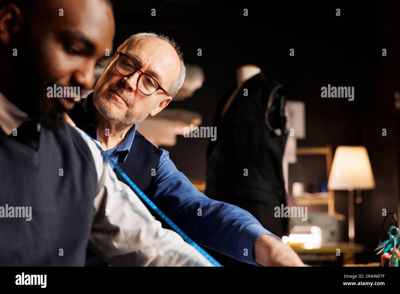 Expert elderly suitmaker sizing up stylish client arm proportions for ...