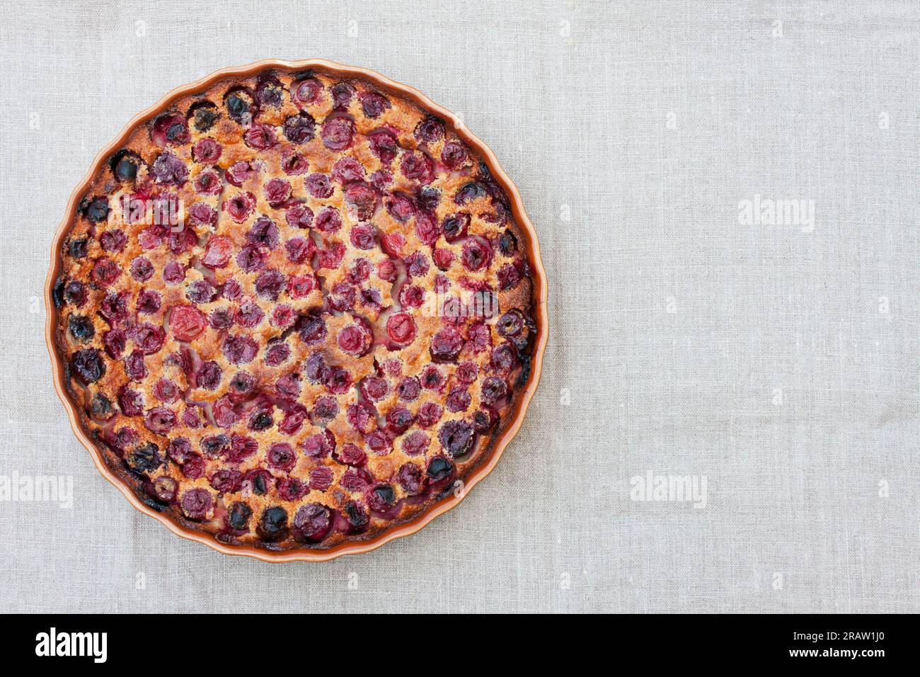 Delicious cherry clafoutis in round baking dish on light background ...