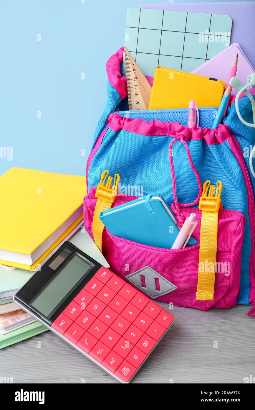 Color school backpack with calculator, books and eyeglasses on grey ...