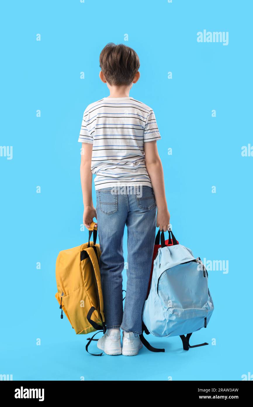 Little schoolboy with backpacks on blue background, back view Stock ...