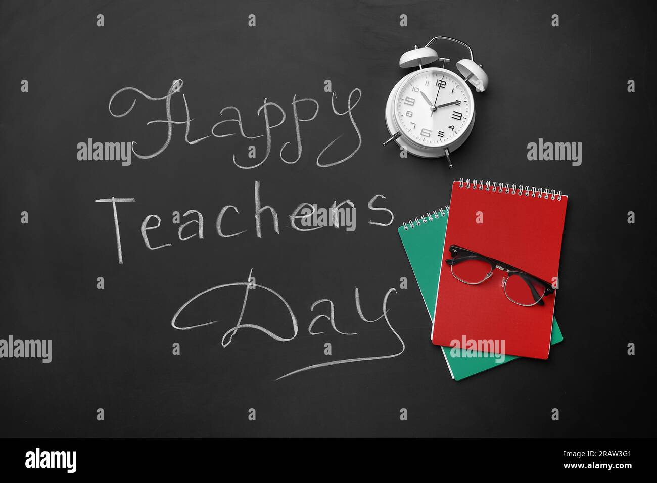 Notebooks, alarm clock and text HAPPY TEACHERS DAY on black chalkboard ...