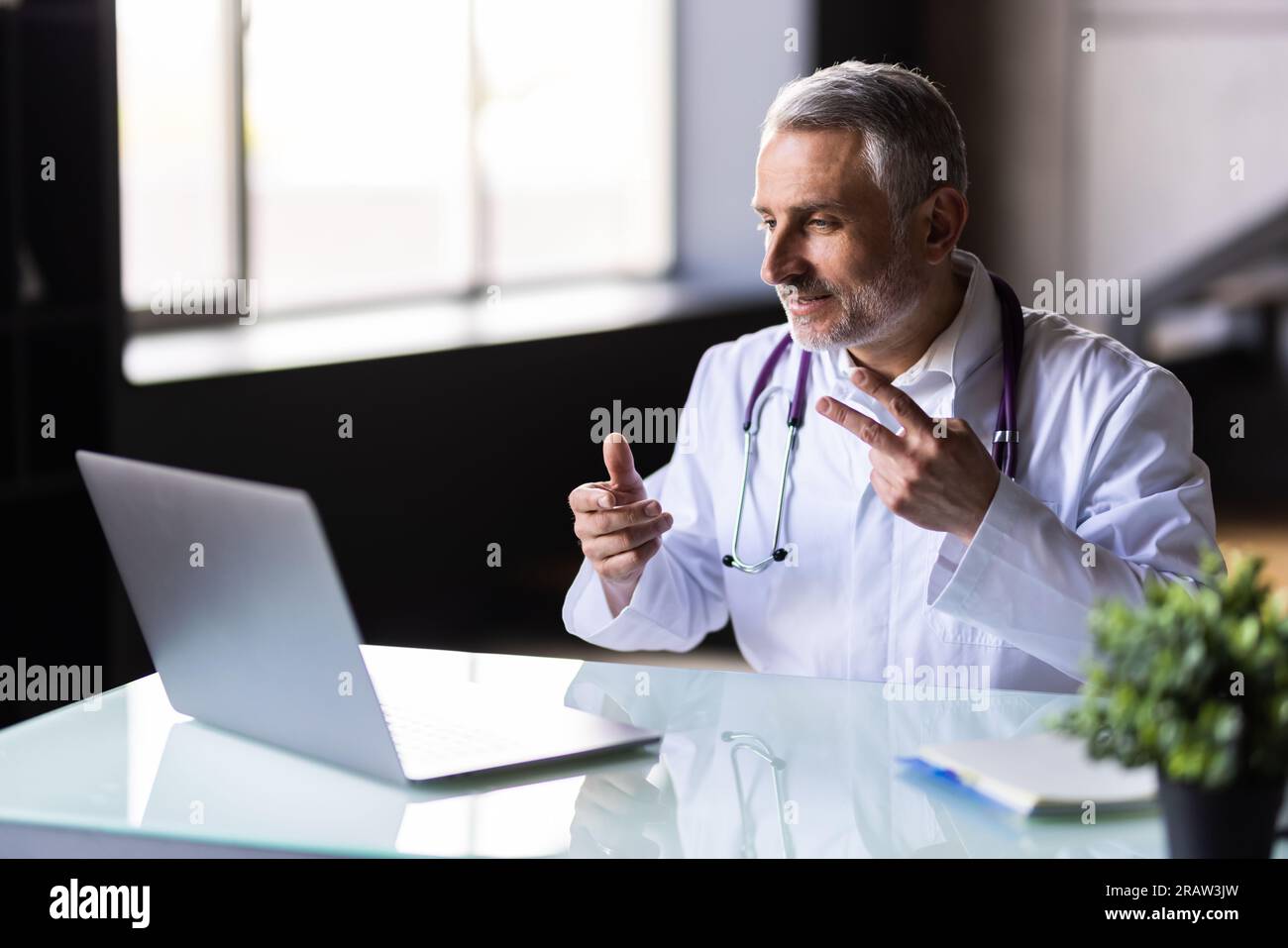 Doctor man sitting at the desk at his working place and smiling at ...