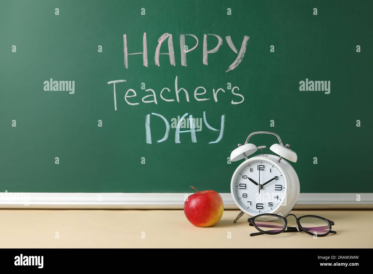 Text HAPPY TEACHERS DAY on green chalkboard with alarm clock, apple and ...
