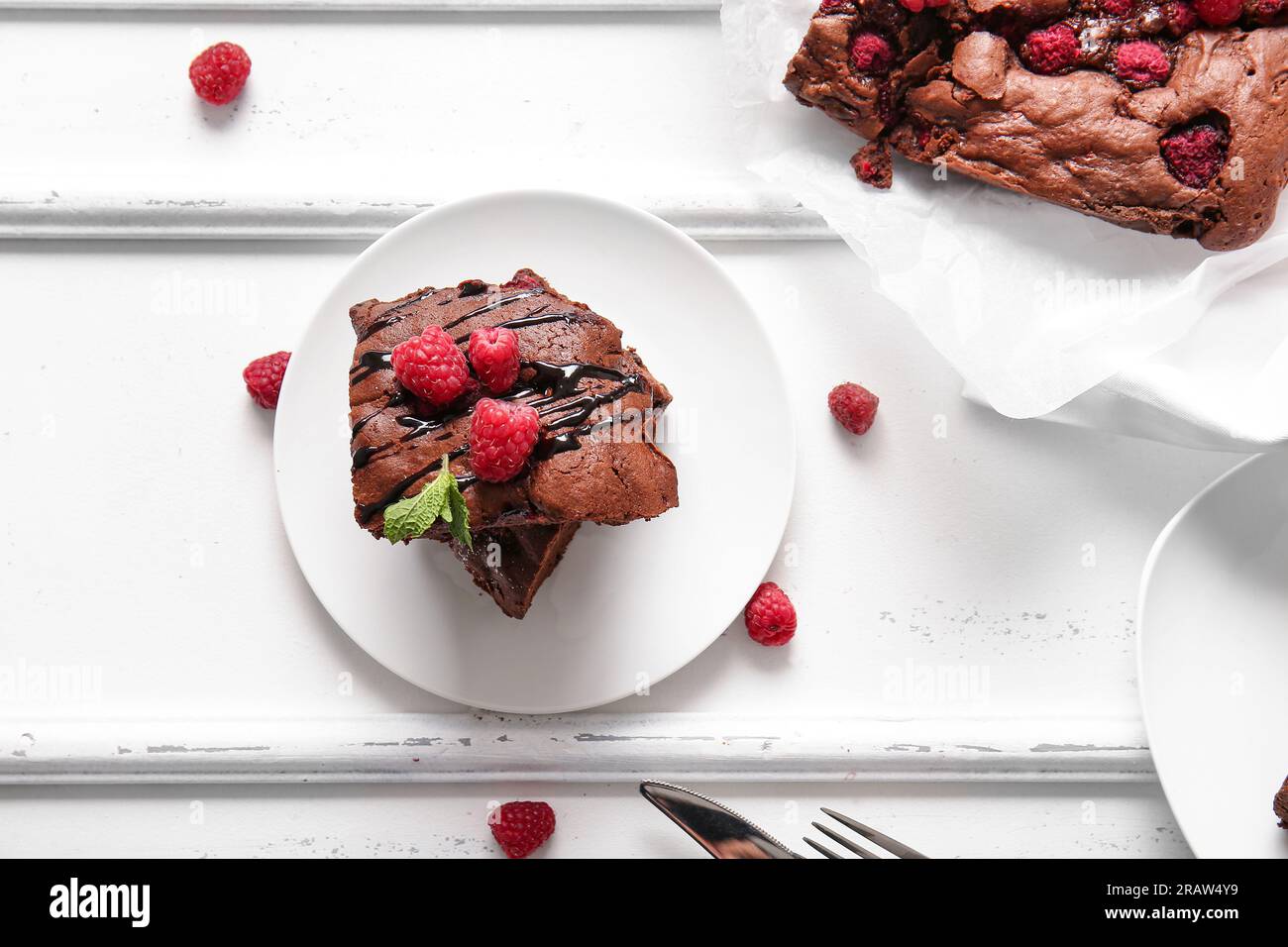 Plate and baking paper with raspberry chocolate brownie on white ...
