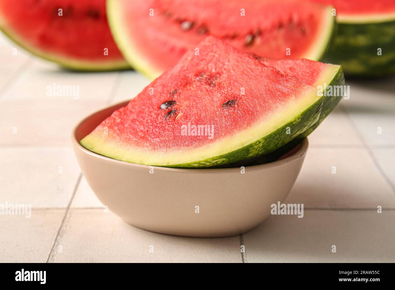 Bowl with pieces of fresh watermelon on white tile table Stock Photo ...