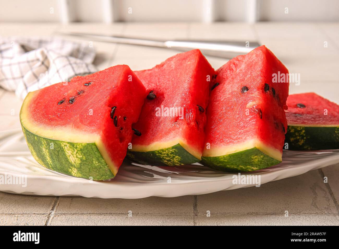 Plate with pieces of fresh watermelon on white tile table Stock Photo ...