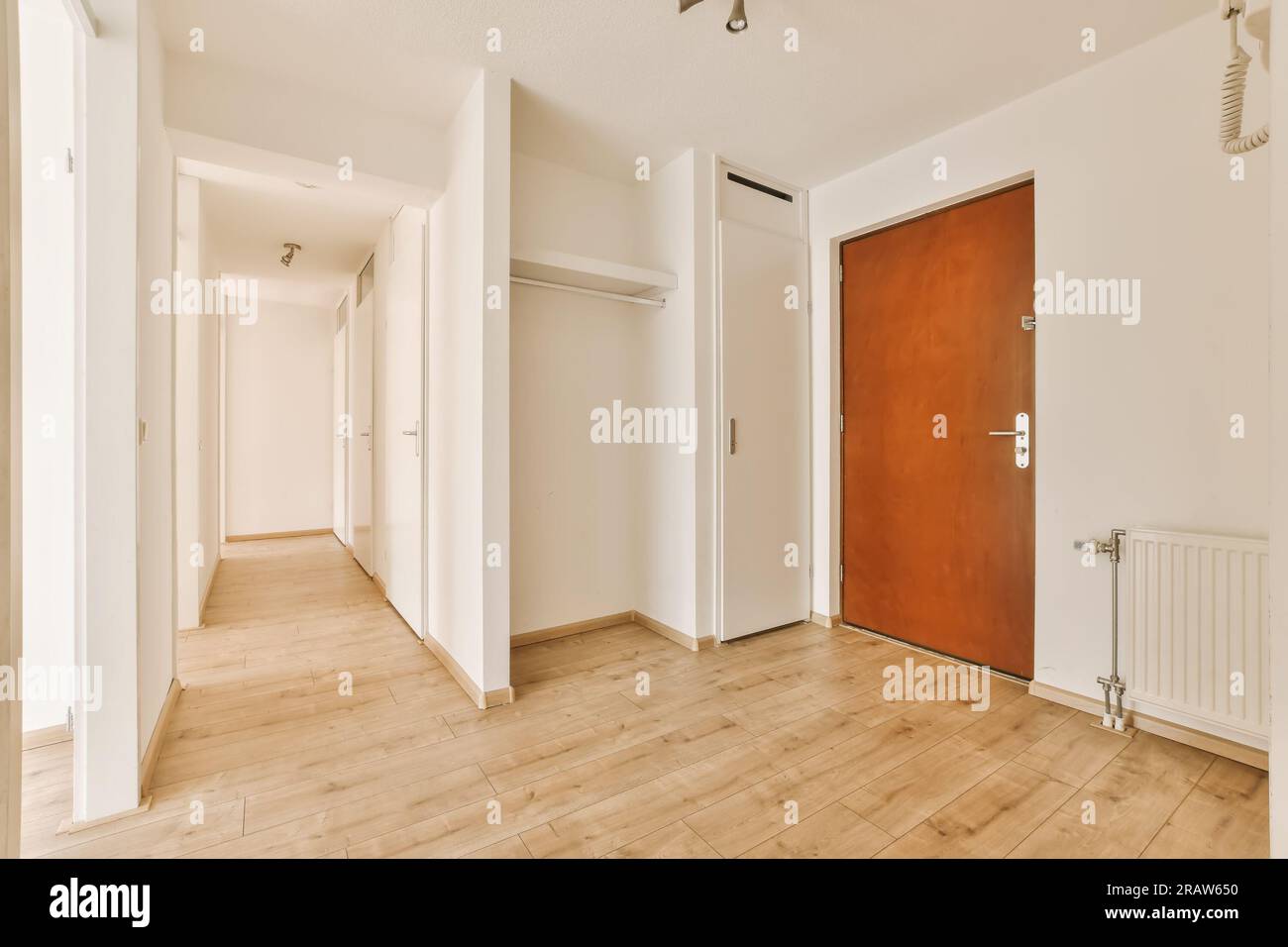 an empty room with white walls and wood flooring, there is a bright red ...