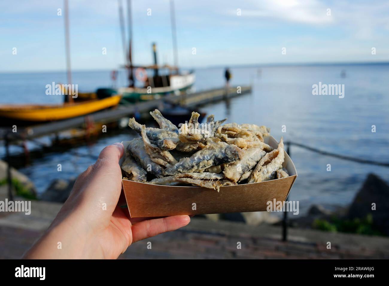 hand holding small fried fish at an seaside restaurant Stock Photo - Alamy