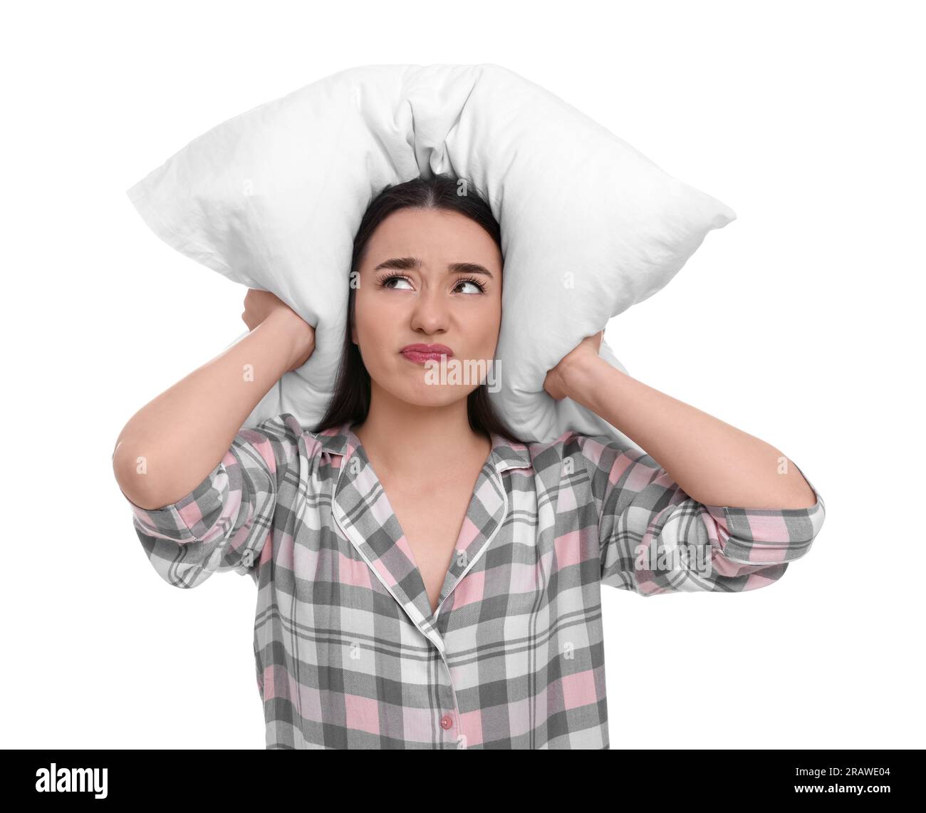 Tired young woman covering ears with pillow on white background ...