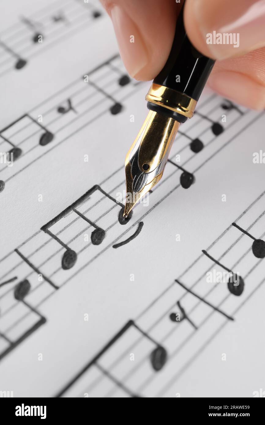 Woman writing musical notes with fountain pen on sheet of paper ...