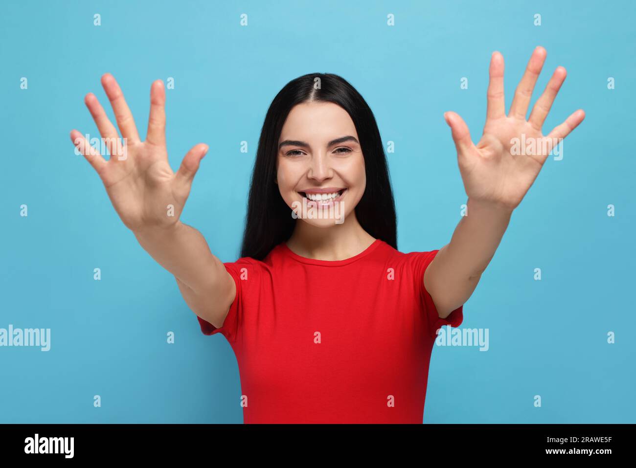 Happy woman giving high five with both hands on light blue background ...